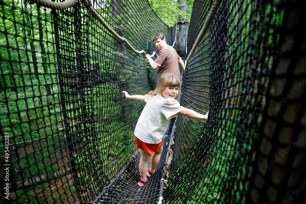 Little preschool girl and father walking on high tree-canopy trail with ...
