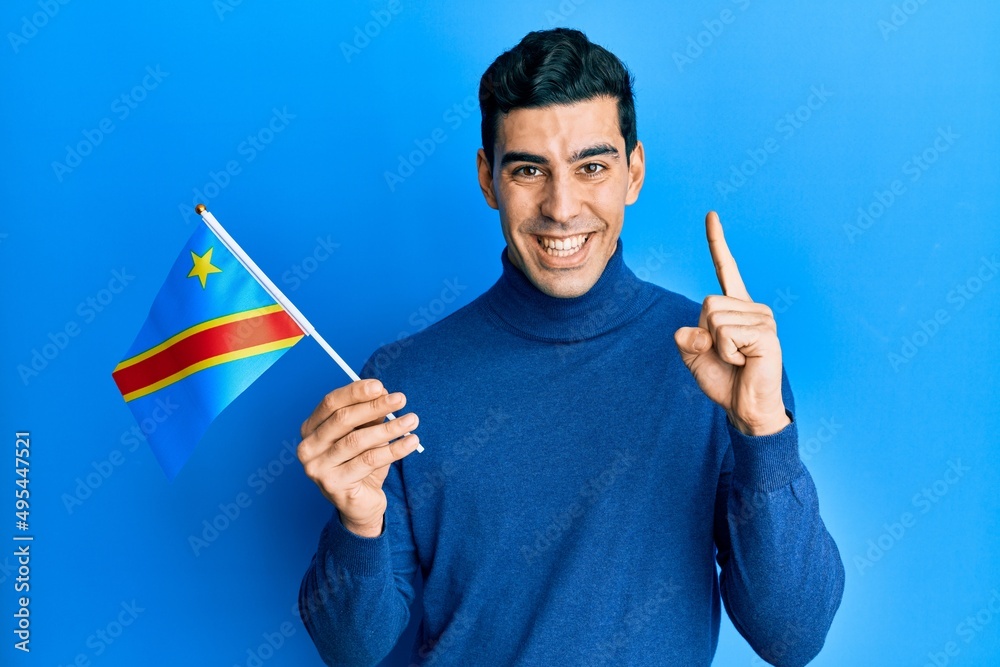 Handsome hispanic man holding democratic republic of the congo flag ...