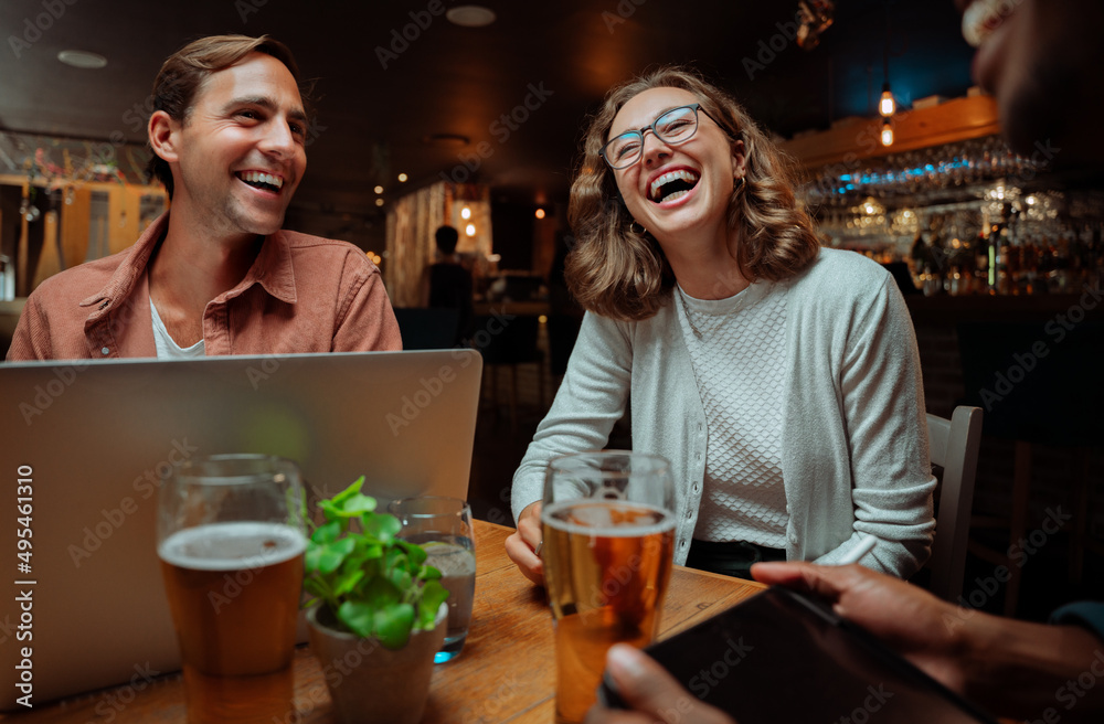 Diverse group of colleagues out for drinks working on laptop and ...