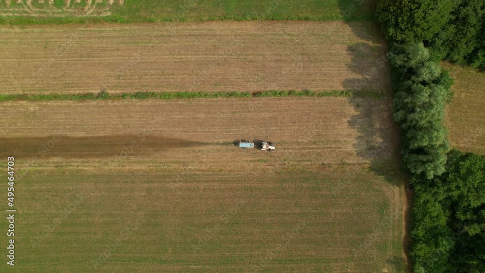 AERIAL, TOP DOWN: Flying above a tractor fertilizing a cultivated field ...