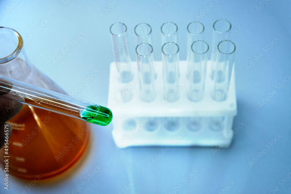 Close up view of transparent glass test flask with brown liquid inside ...