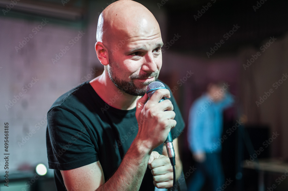 Smiling and witty stand up actor comedian on stage, talking and singing ...