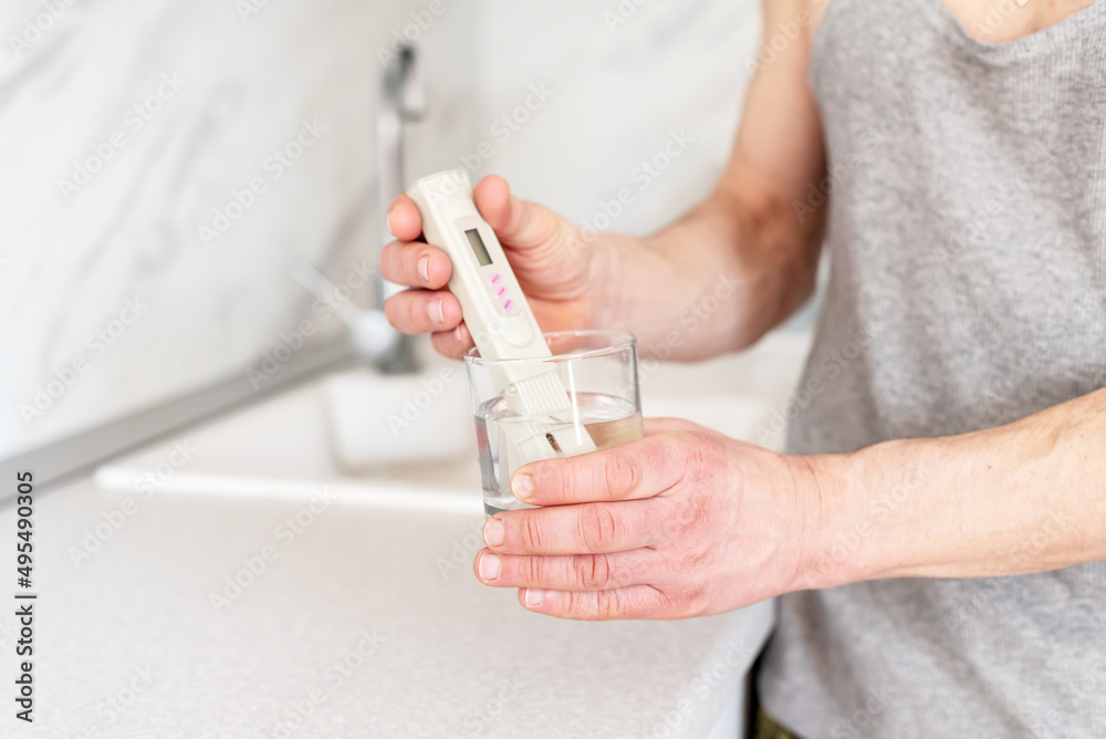 Checking the purity of water at home. Male hands and Glass of water ...