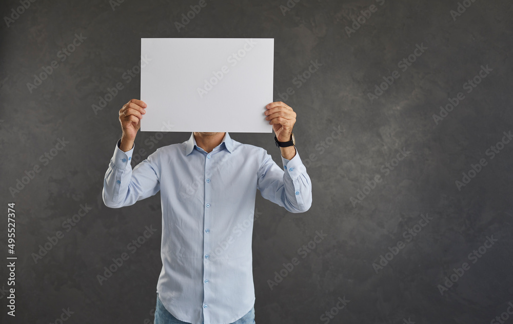 Man holding blank white sheet of paper in front of his face showing ...