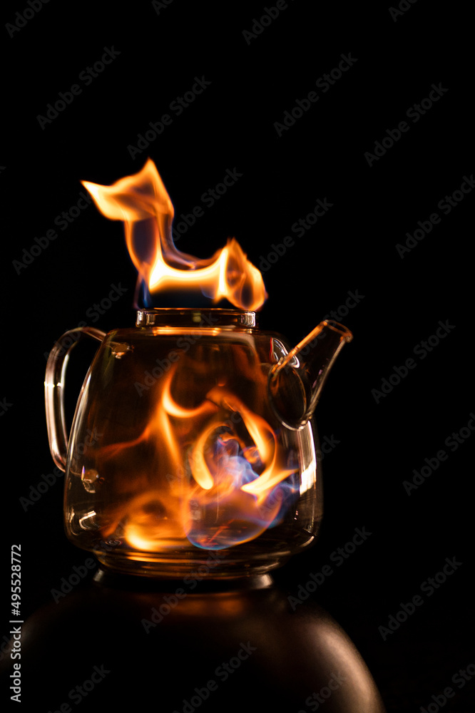 Fire within a see through glass tea pot showing beautiful orange and ...