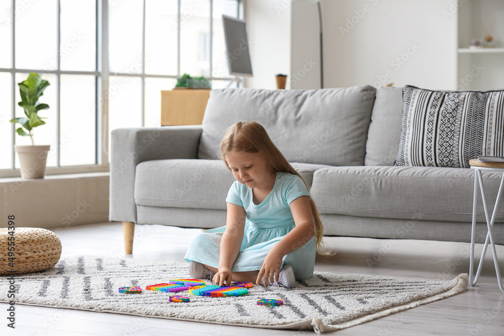Pretty girl sitting on floor and playing with pop it fidget toys in ...