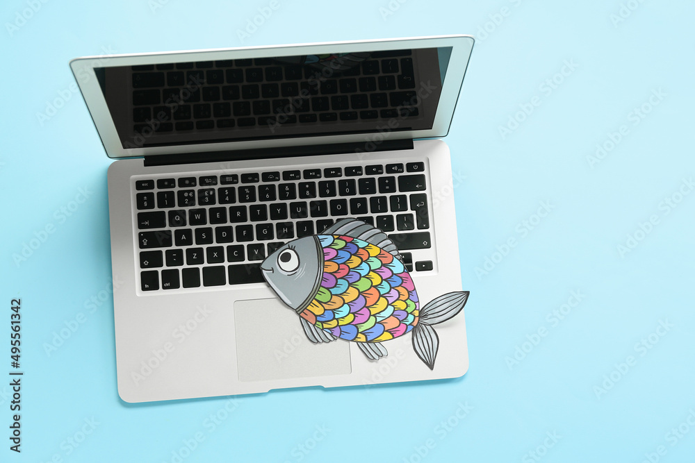 Laptop and paper fish on color background. April Fools Day celebration ...