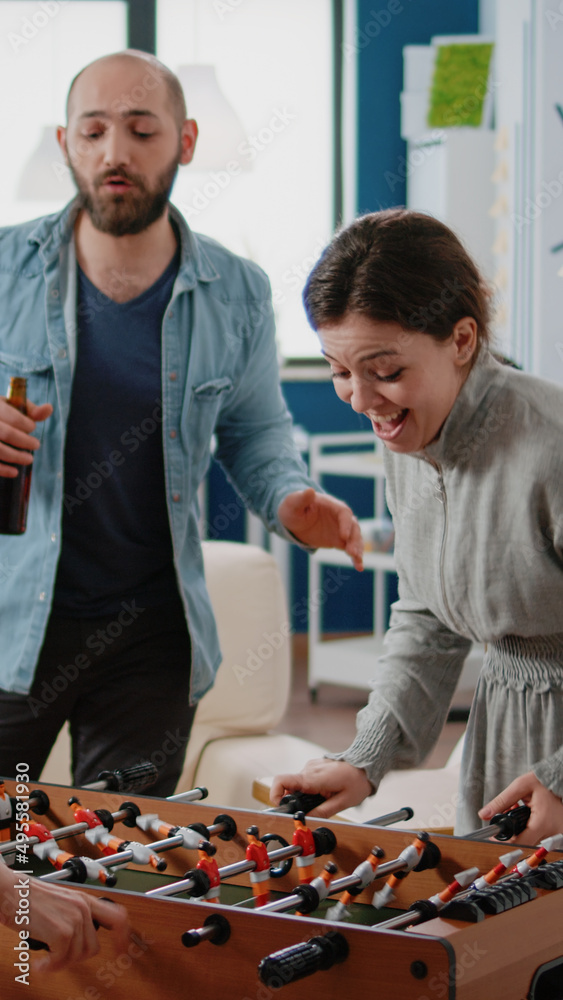 Colleagues playing foosball game and woman winning, having fun with ...