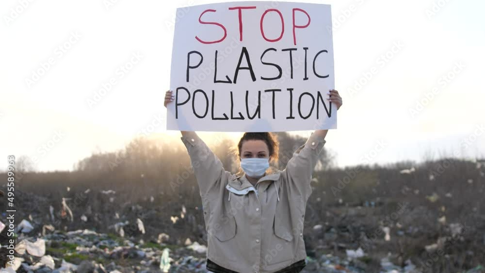Sad woman volunteer activist stands at big landfill site with garbage ...