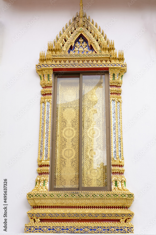 Foto de Vertical shot of ancient golden temple windows on a white wall ...