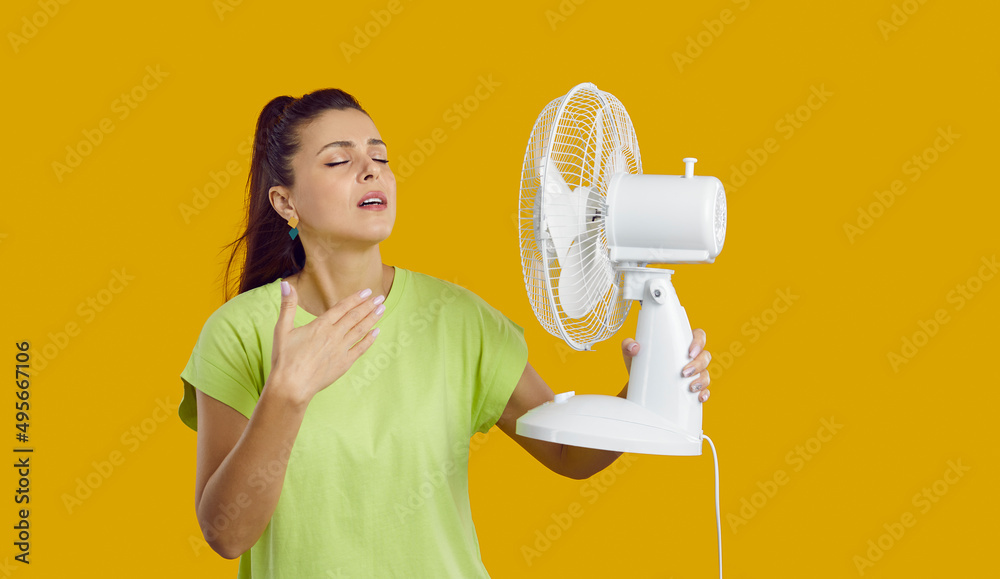 Young woman with a fan in her hand is exhausted from the heat, trying ...