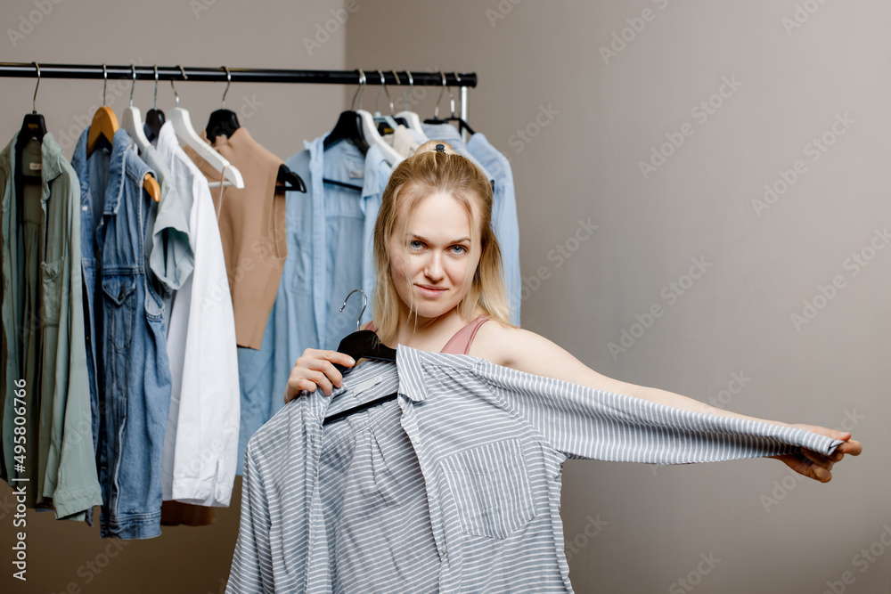 beautiful young woman tries on clothes in the wardrobe and looks at the ...