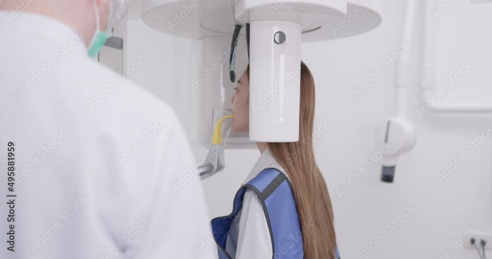 On a panoramic x-ray machine, the dentist aligns the bite of a woman ...