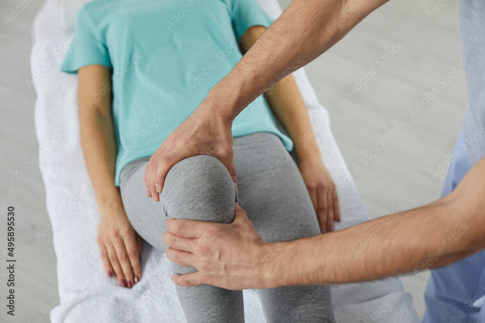 Male therapist massaging knee of female patient during physiotherapy ...