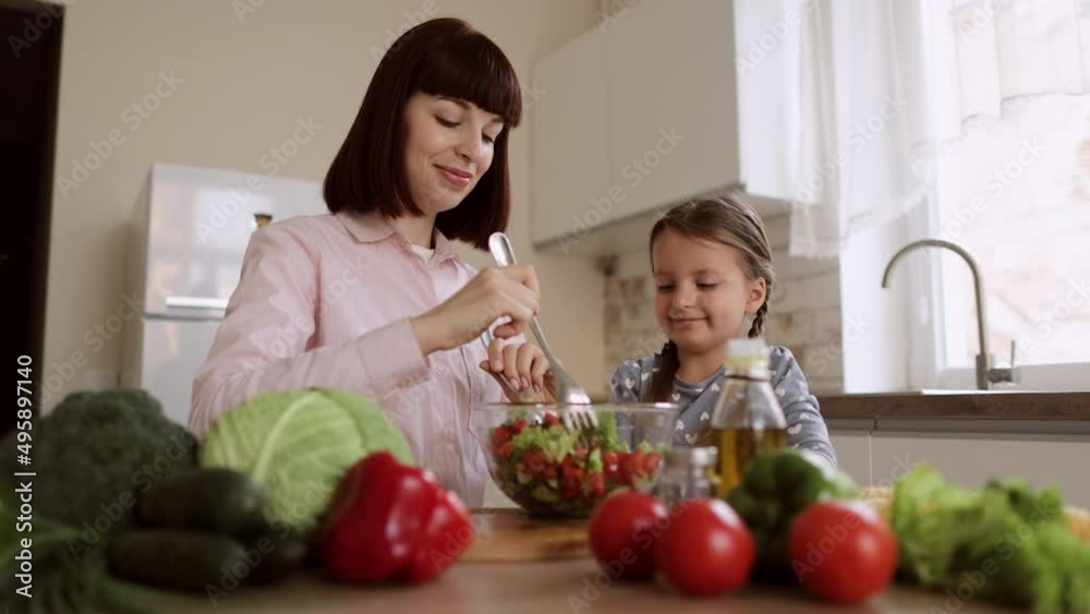 Little adorable daughter helps young mother cook healthy dinner In ...