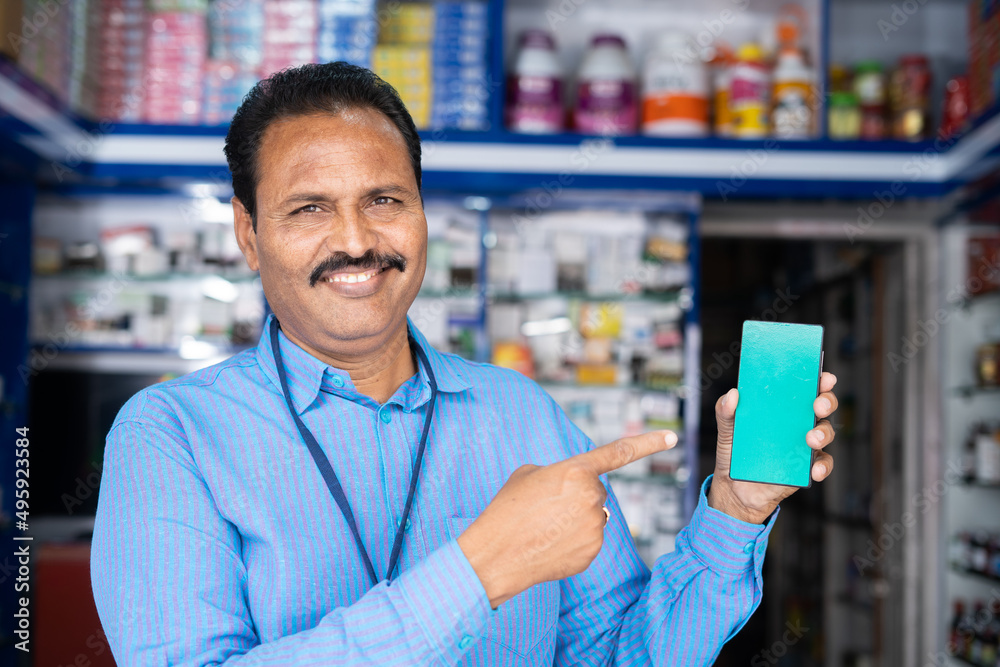 smiling medical shop owner showing green screen mobile phone by looking ...