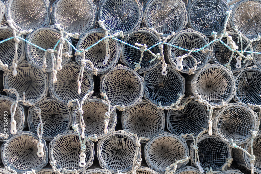 A stack of cylindrical crab or lobster traps stored on a jetty at ...