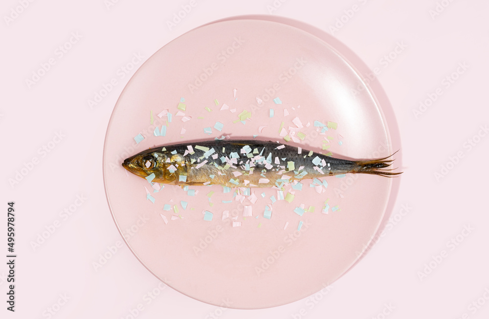 Fish covered microplastic on a pink plate. Impact of micro plastic on ...