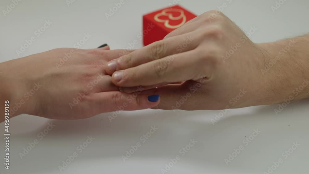 Close-up male hand putting on engagement ring on female palm at white ...
