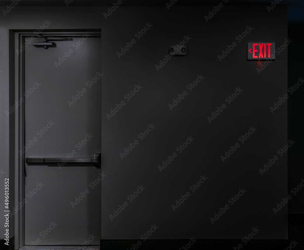 Red exit sign bright up in the dark show direction to emergency door ...