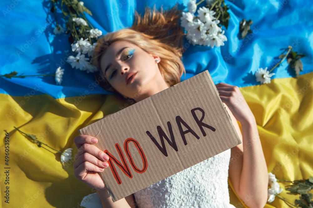 NO WAR! Woman lying on ukrainian yellow blue flag with protest signs ...
