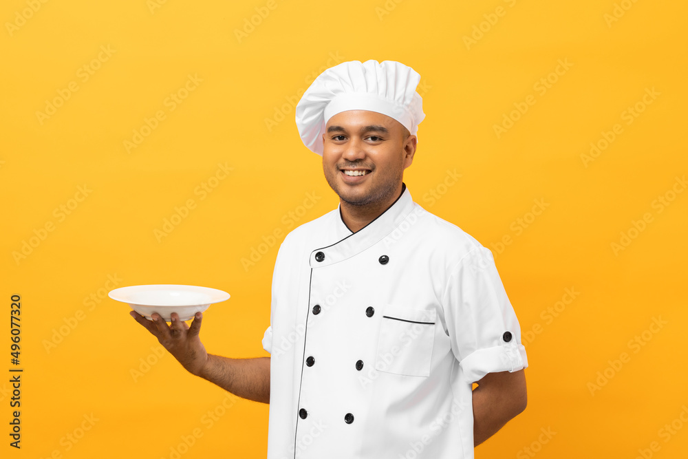 Attractive Young handsome asian man chef in uniform holding empty plate ...