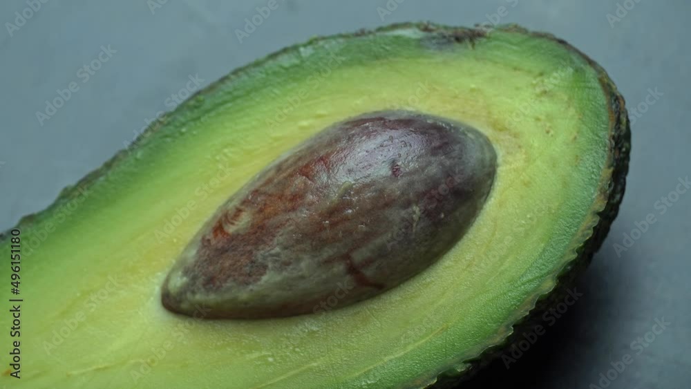 Half of an avocado with a stone rotates in a circle on a black ...