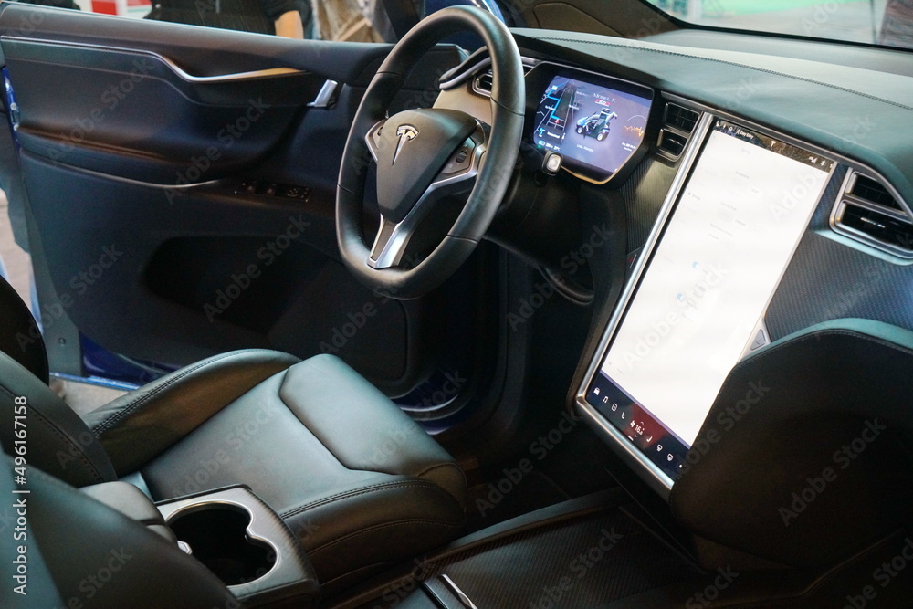 The interior of a Tesla electric car with steering wheel and dashboard ...