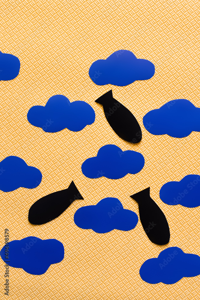 Top view of paper bombs near carton clouds on textured yellow ...