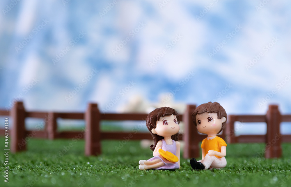 Cute Miniature dolls boy and girl sitting on the grass ground in the ...