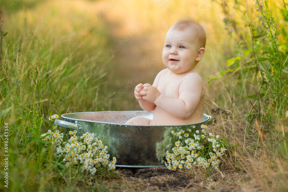 cute baby is bathing in an iron basin in the garden. outdoor water ...