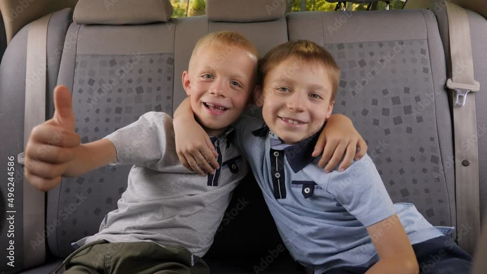 Portrait of two little boys in identical T-shirts in the back seat of a ...