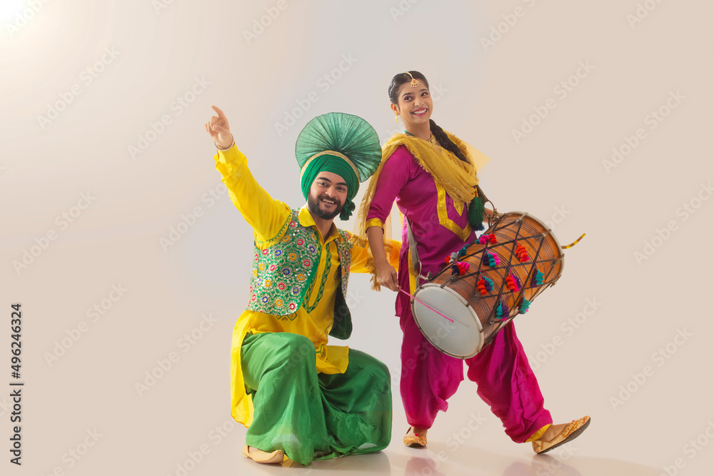 Sikh couple performing bhangra and playing drum during Baisakhi ...