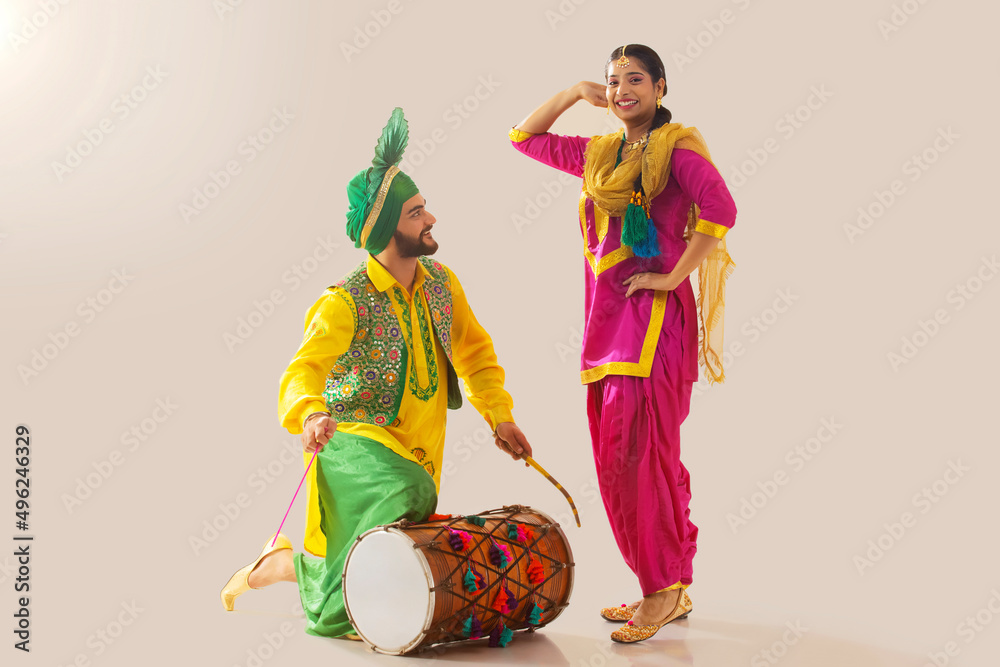 Foto de Sikh couple performing bhangra and playing drum during Baisakhi ...