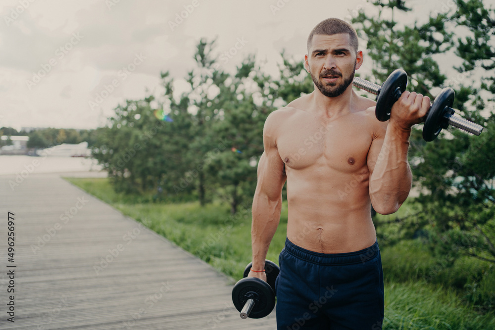 Strong muscular bodybuilder prepares for athletic competition, raises ...