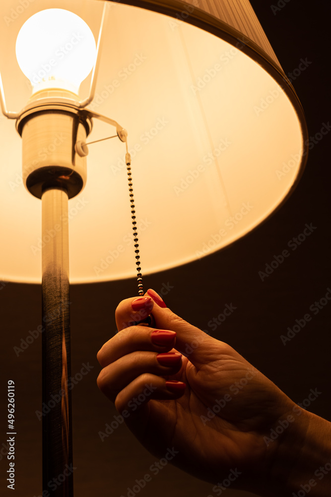 woman pulling the switch chain of a floor glowing lamp Stock Photo ...