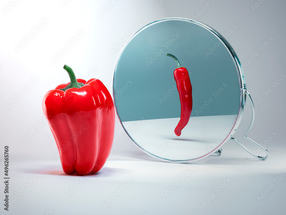 Large Red bell pepper in front of a mirror with a reflection of a thin ...