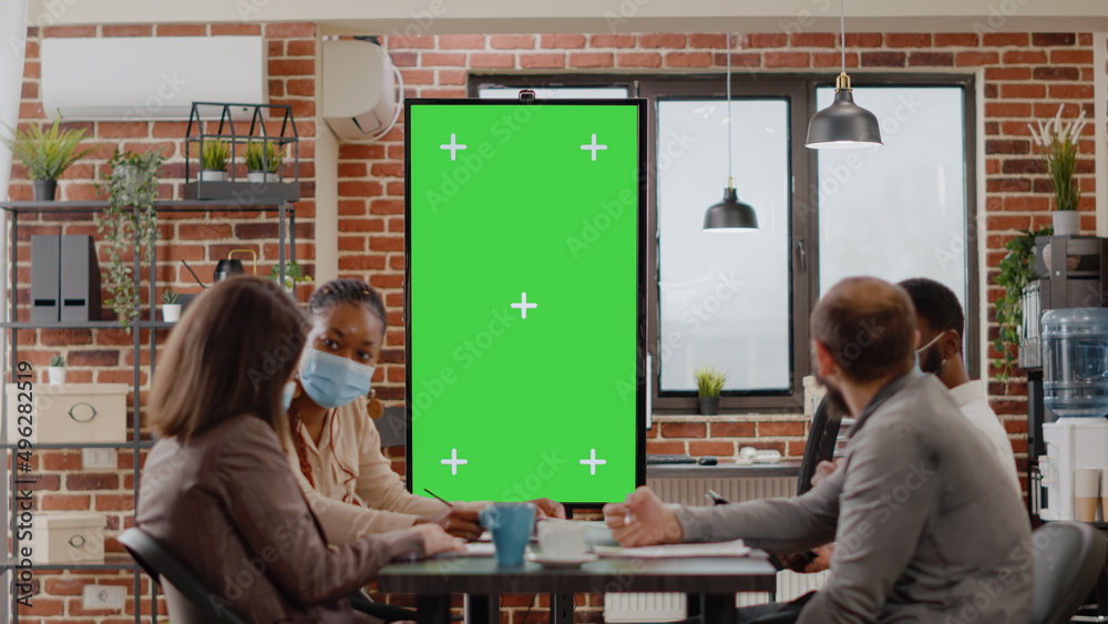 Team of colleagues working with vertically green screen on display ...