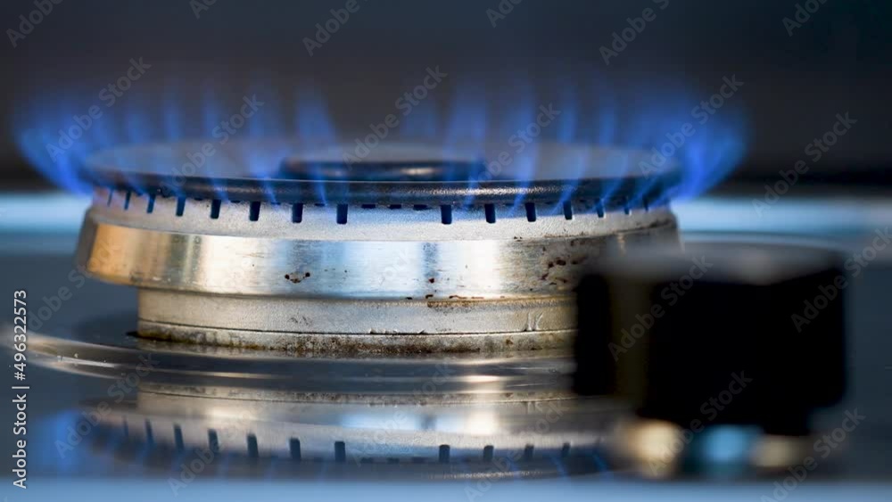 Brûleur d'une cuisinière à gaz qu'une main vient allumer puis éteindre ...