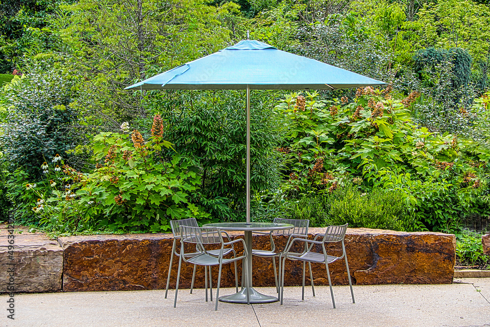 Metal outdoor table and chairs with green umbrella in front of wall ...
