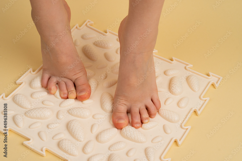 children's feet on a beige orthopedic rug on a beige background ...