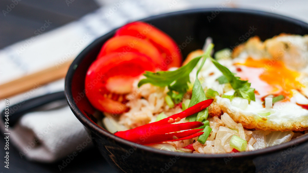 Japanese-style fried rice served in a black bowl with a fried egg and ...