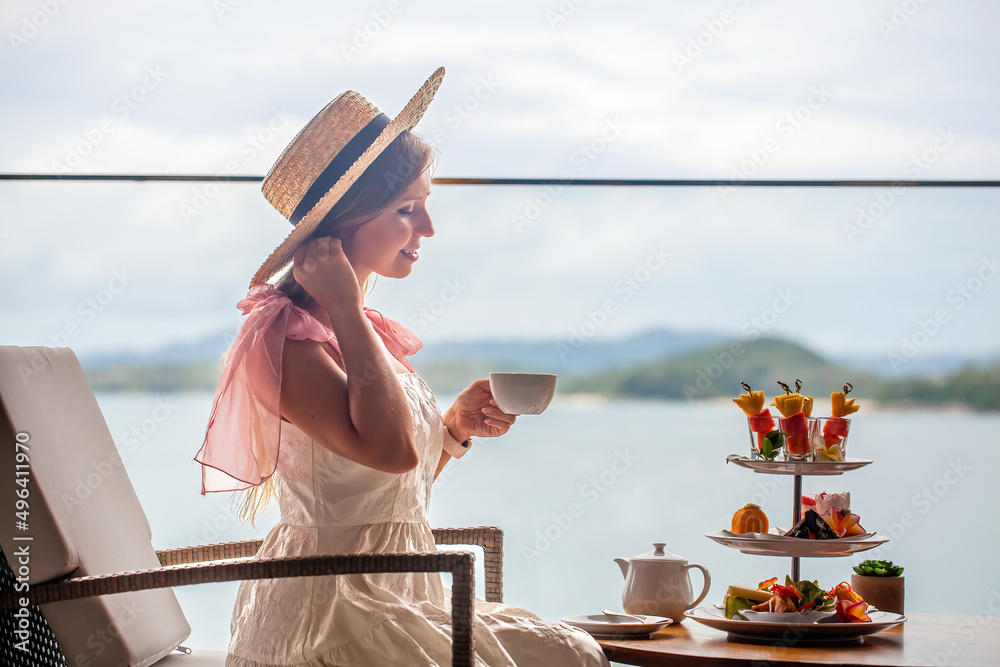 Young lady in white dress drinking tea on Afternoon tea with mini ...
