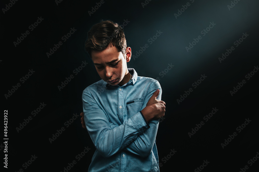 The concept of domestic violence. The sad teenage boy crossed his arms ...