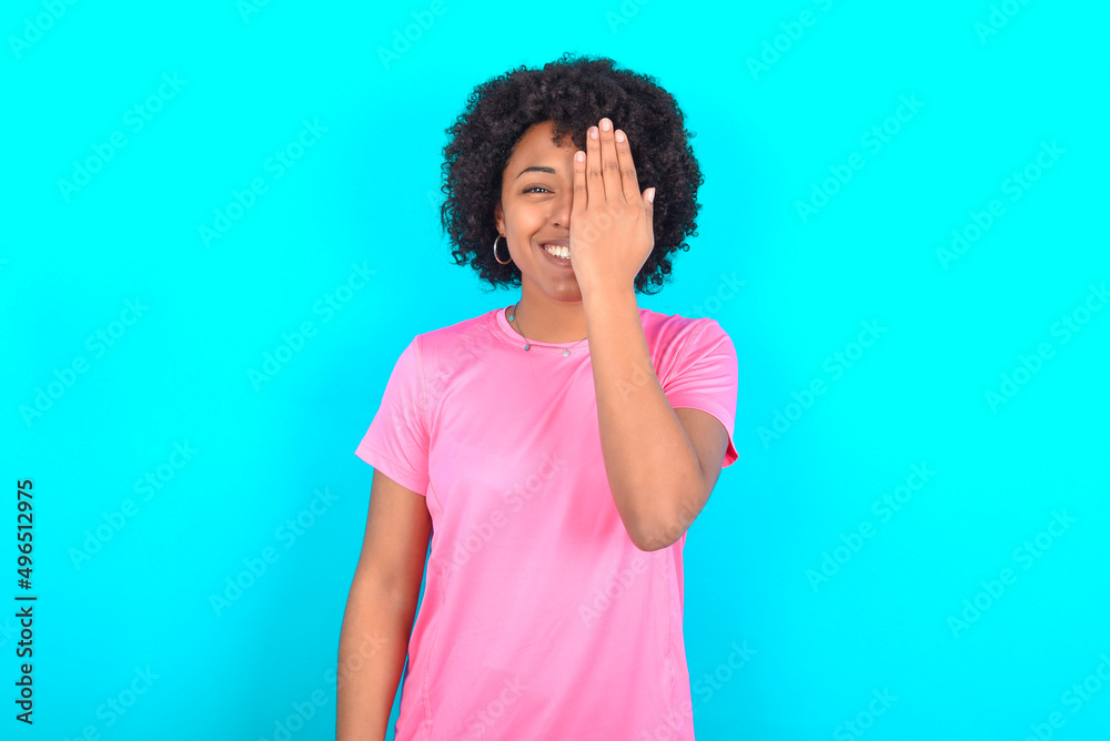 young girl with afro hairstyle wearing pink T-shirt over blue ...