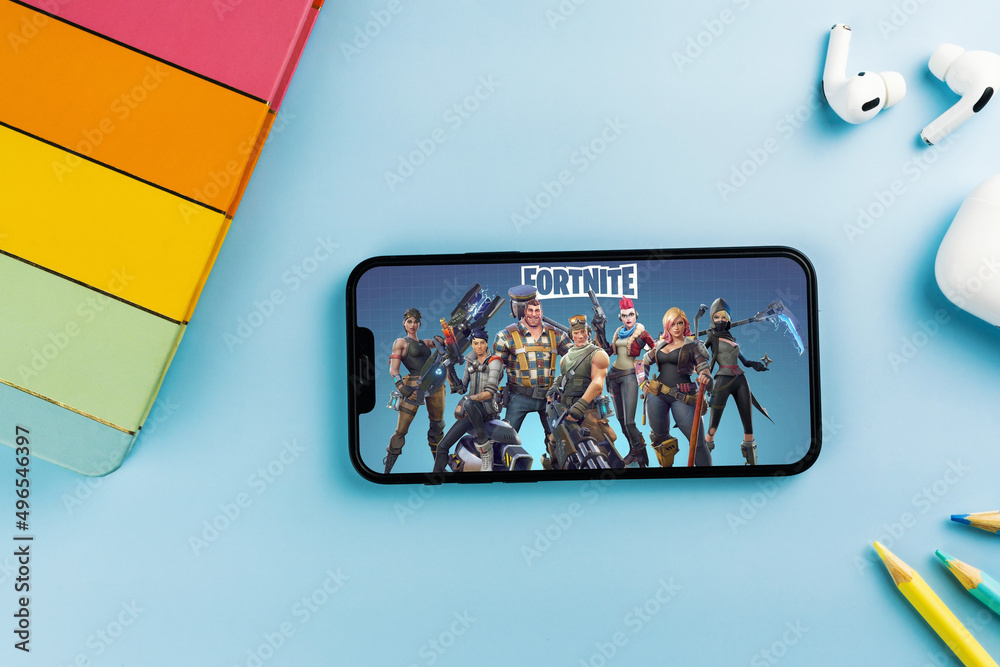 Fortnite mobile game app on the smartphone screen. Blue background with ...
