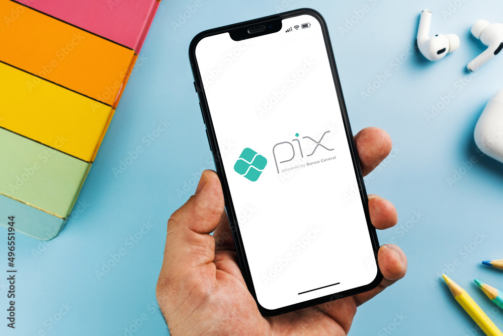 Man holding a smartphone with Pix app on the screen. Blue background ...