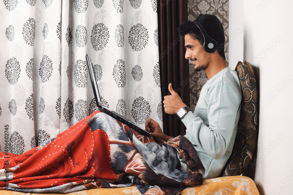Young bearded Indian boy using computer laptop doing happy thumbs up ...