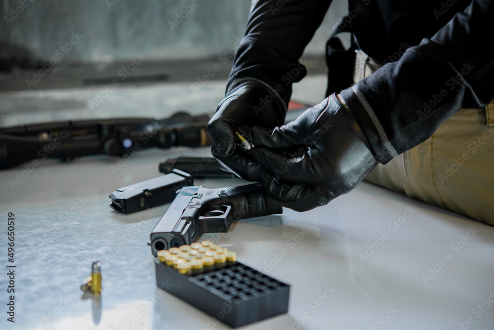 Asian male wearing black leather gloves with gun in hand,loading ...