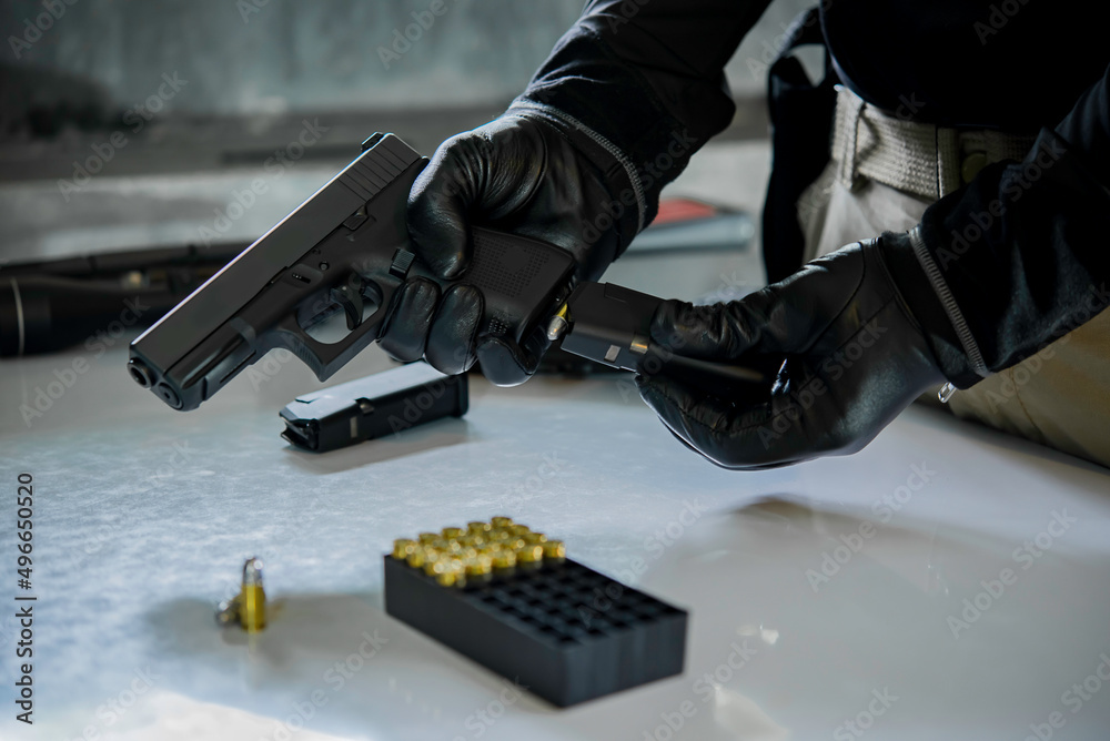 Asian male wearing black leather gloves with gun in hand,loading ...